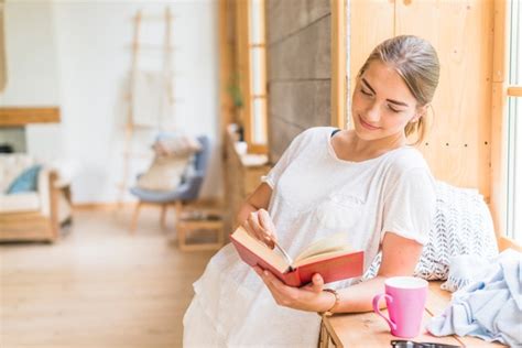 Libro De Lectura Sonriente De La Mujer Joven En Casa Foto Gratis