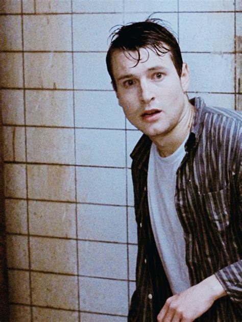 A Man Standing In Front Of A Tiled Wall