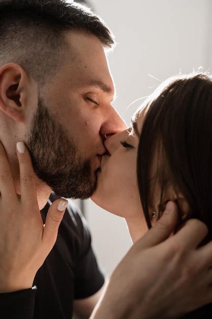 Pareja enamorada abrazándose y besándose en el sofá en casa relaciones