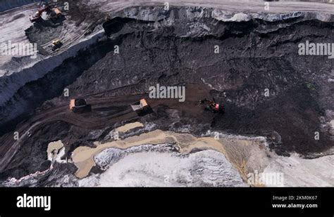 A Large Yellow Dump Truck Pulls Up To An Oxcavator Pouring Soil Into
