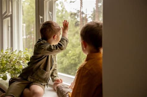 Niños sentados en el alféizar de la ventana y esperando que alguien