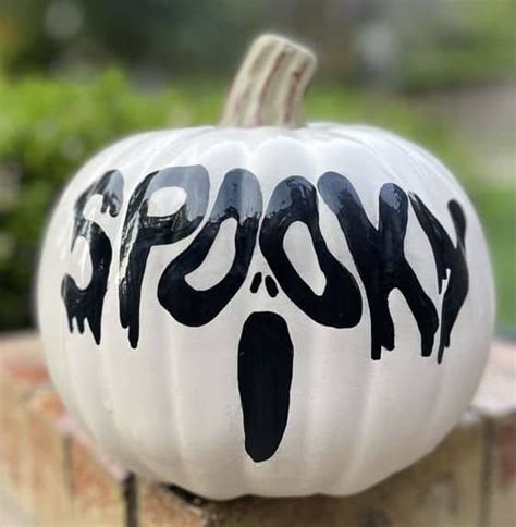 A Painted Pumpkin Sitting On Top Of A Brick Wall With The Word Ghost