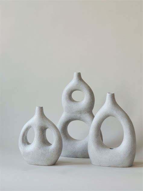 Three White Vases Sitting Next To Each Other