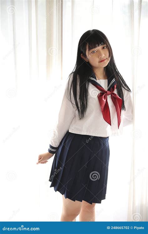 Asiatische Schülerin In Der Oberschule Die Mit Einem Kosmoblütengarten Sitzt Stockfoto Bild