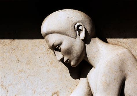 Una Estatua De Un Hombre Con La Cabeza Apoyada En Un Muro De Piedra