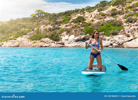 Woman In A Bikini On A Stand Up Paddle Board Over Turquoise
