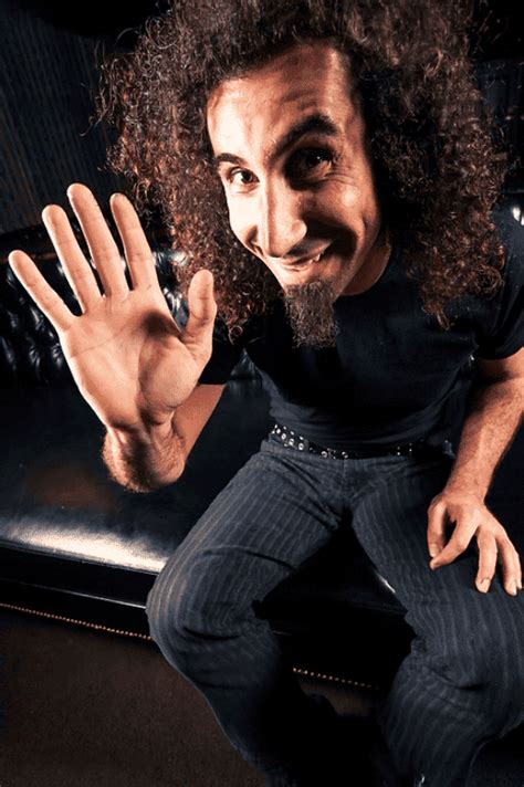A Man With Long Curly Hair Sitting On Top Of A Black Chair Holding His