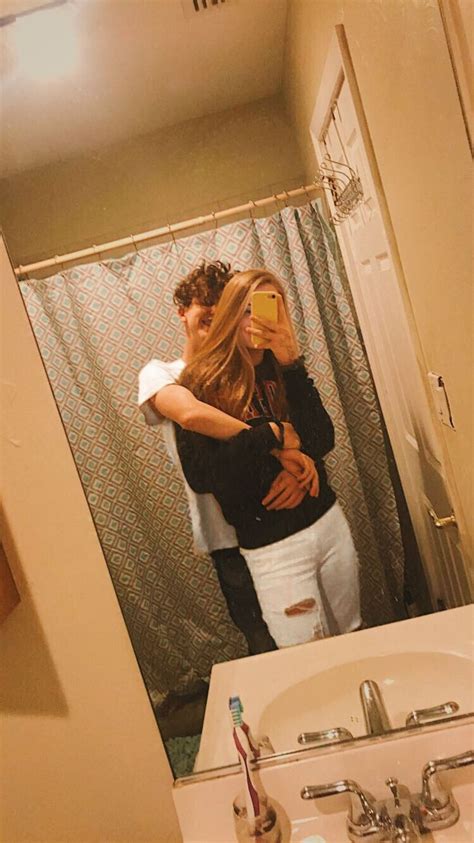 Two People Are Taking A Selfie In The Bathroom Mirror One Person Is Holding His Arm Around The