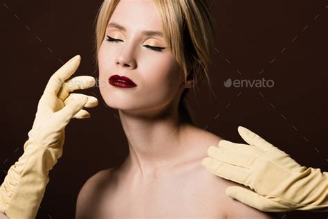 Naked Blonde Girl With Closed Eyes And Human Hands In Yellow Gloves On