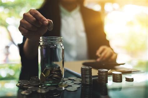 Premium Photo Closeup Of A Businesswoman Putting Coins In A Glass Jar