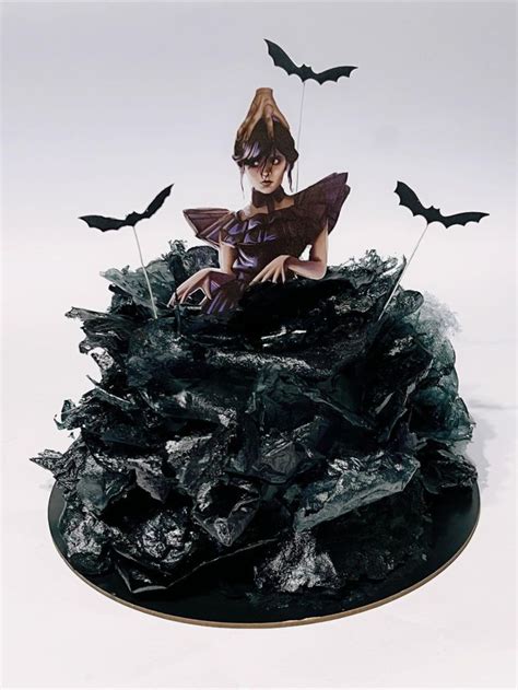 A Woman Sitting On Top Of A Pile Of Black Paper With Bats Flying Around Her