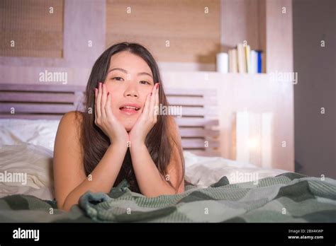 Lifestyle Portrait Of Young Beautiful And Happy Asian Chinese Woman Lying In Bed At Home Bedroom