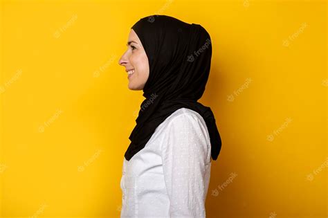 Premium Photo Young Muslim Woman In Hijab Looks To The Side And Smiles On A Yellow Background