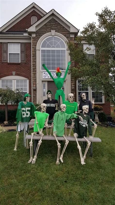 A Group Of Skeletons Sitting On Top Of A Bench In Front Of A House