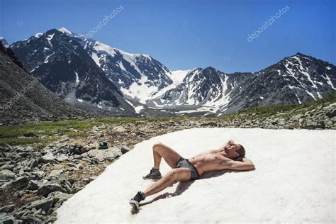 hombre desnudo en montaña de hielo contra el cielo Joven tirado en la