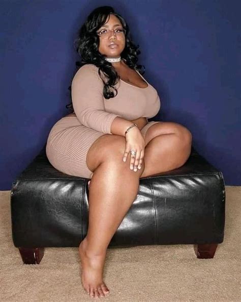 A Woman Sitting On Top Of A Black Leather Ottoman With Her Legs Spread