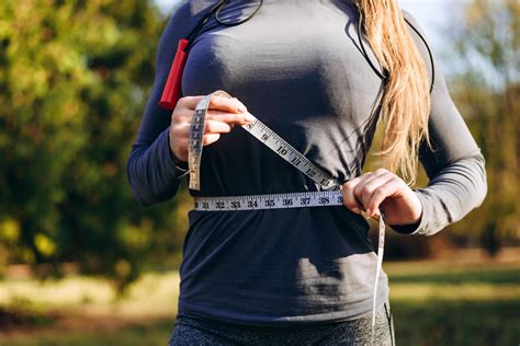 Athletic Slim Woman Measuring Her Waist By Measure Tape After Workout