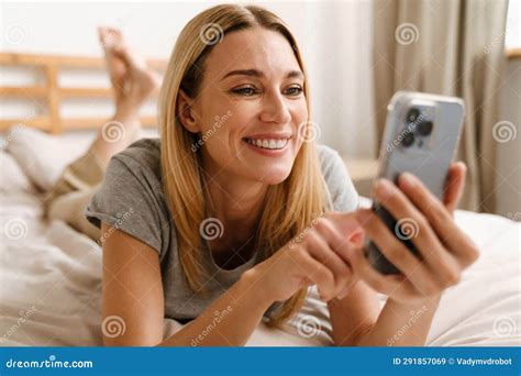 Blonde Woman Smiling And Using Cellphone While Resting On Bed Stock Image Image Of Mobilephone