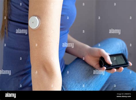 Girl Sitting With Flash Glucose Monitor Patch On Her Hand Holding