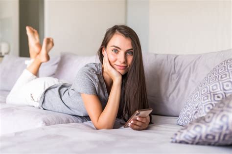 Portrait De Femme Rêveuse Allongé Sur Le Ventre Sur Le Canapé Tenant Un