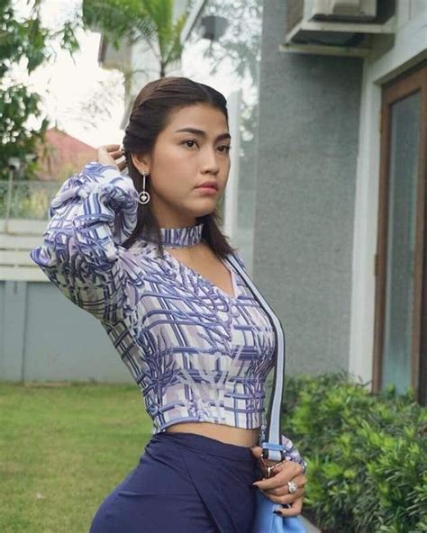 A Woman Is Standing In Front Of A House With Her Hand On Her Hip And