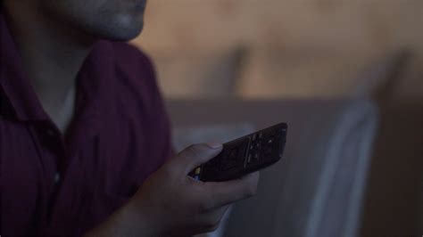 Closeup Shot Of A Man Using Remote Control To Change Televisio