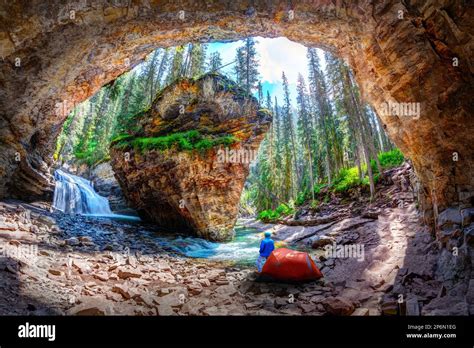 Hiker Stands Outside His Camping Tent At Hidden Cave With Waterfall And