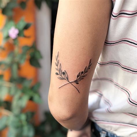 A Woman S Arm With A Tattoo On It That Has An Olive Branch In The Middle